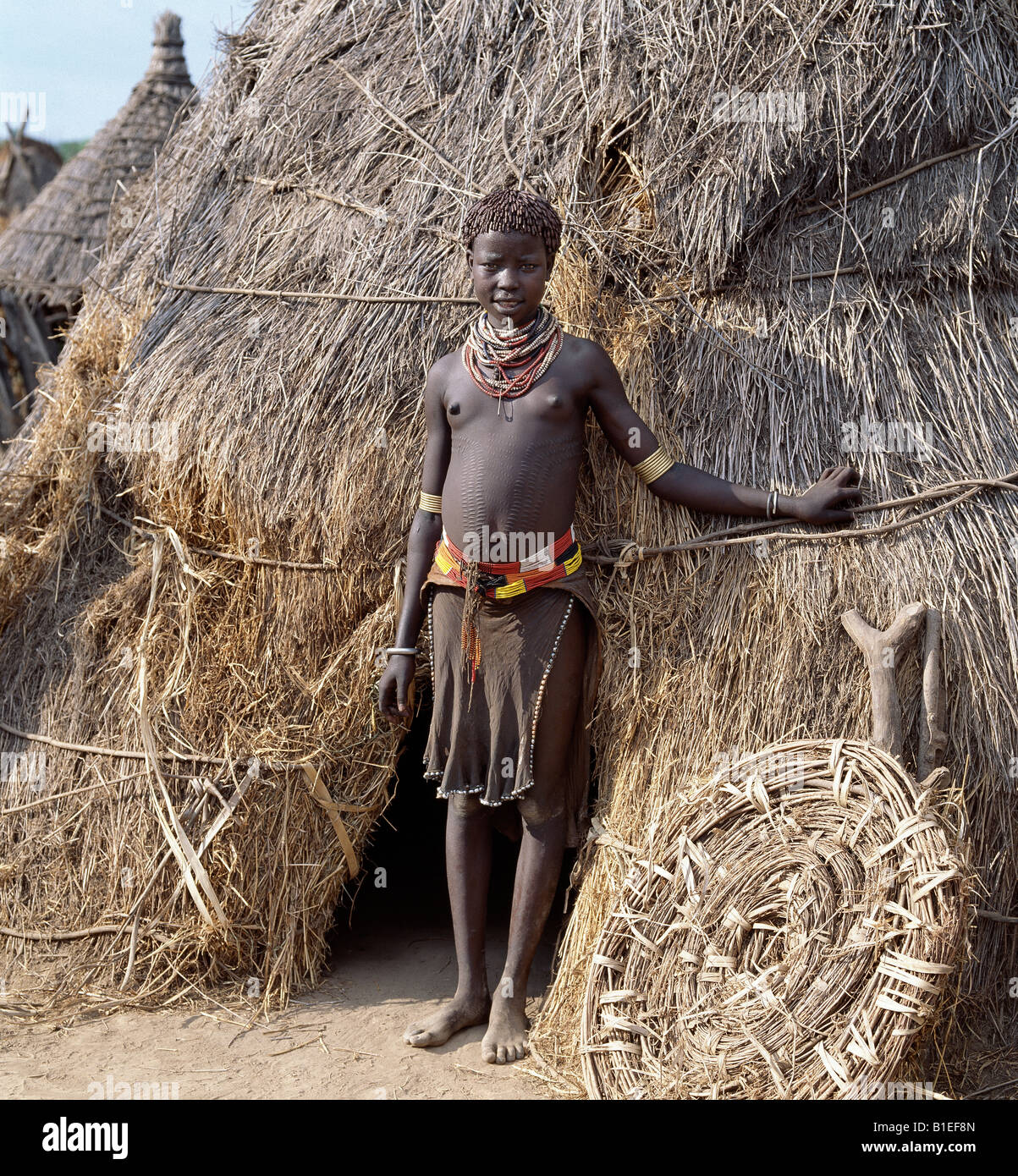 A Karo girl in traditional attire stands outside her family's home ...