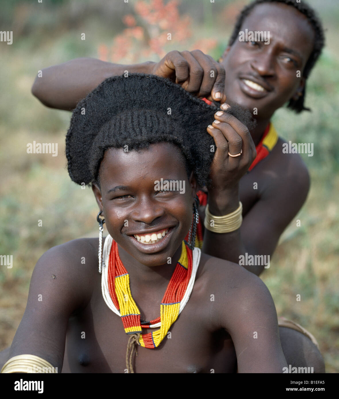An elaborate hairstyle of a young Hamar man nears completion by his ...