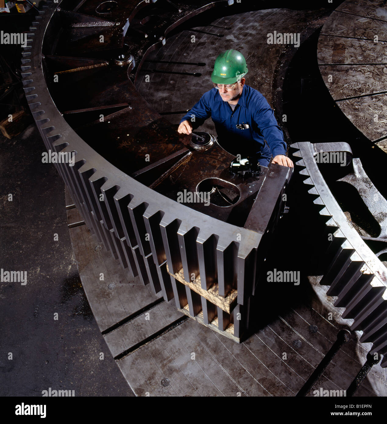 Metal worker checks quality control tolerances on the teeth of large ...