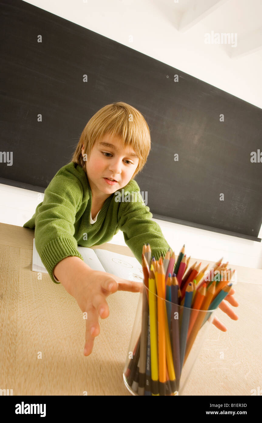 Boy reaching out for a pencil holder Stock Photo - Alamy