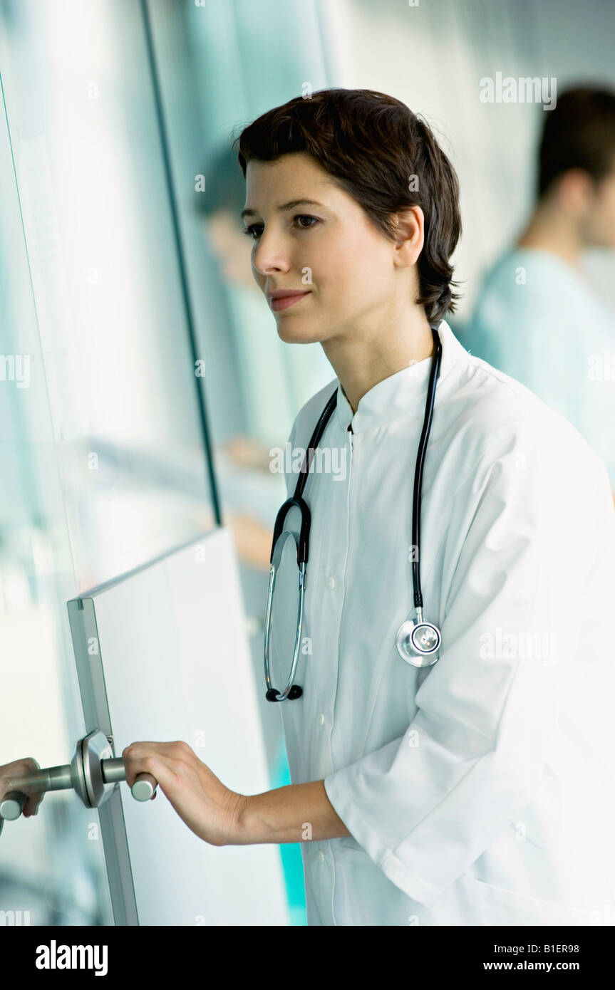 Side profile of a female doctor holding a door handle and smiling Stock ...