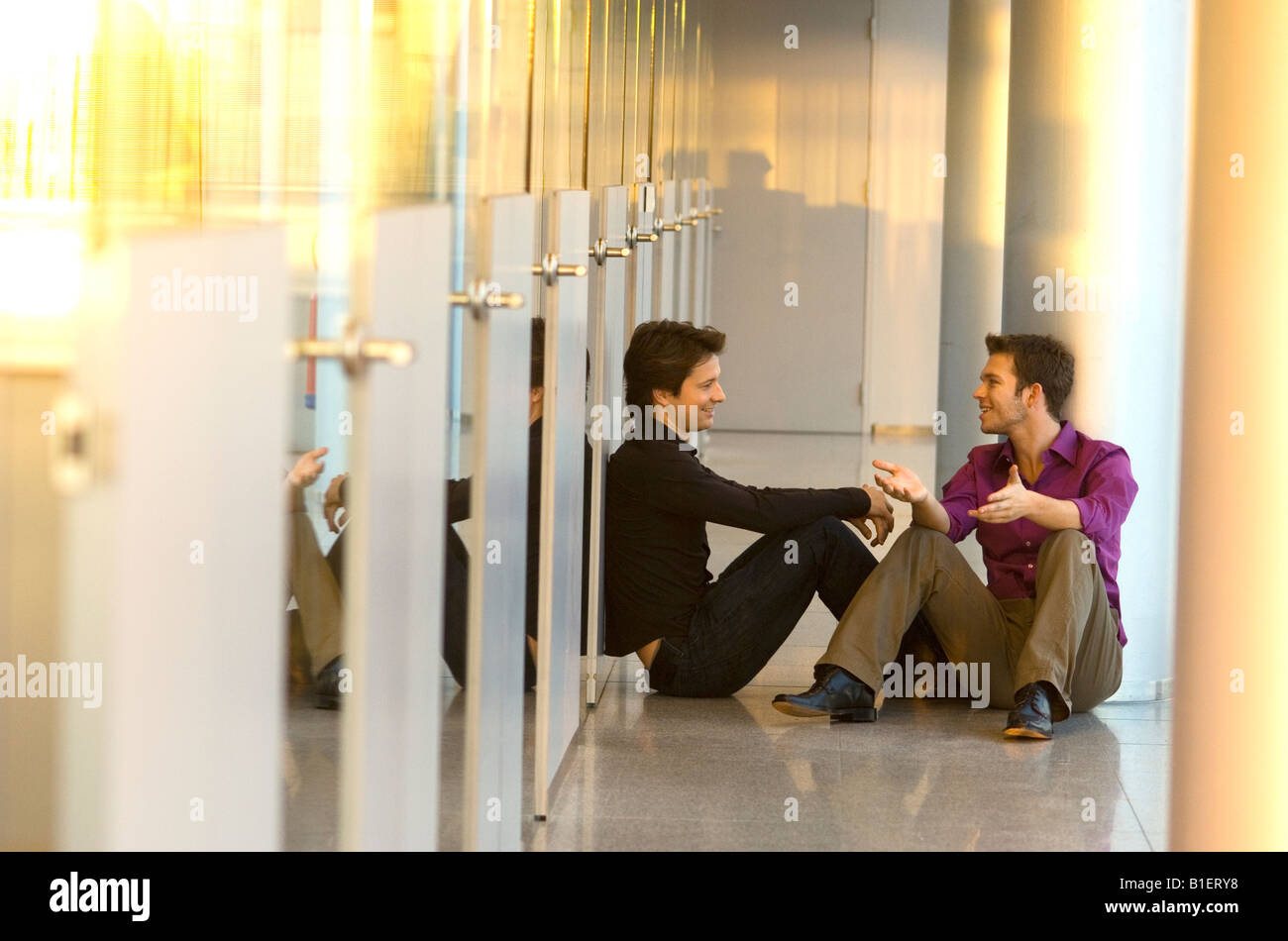 Two businessmen sitting in a corridor and talking with each other Stock ...