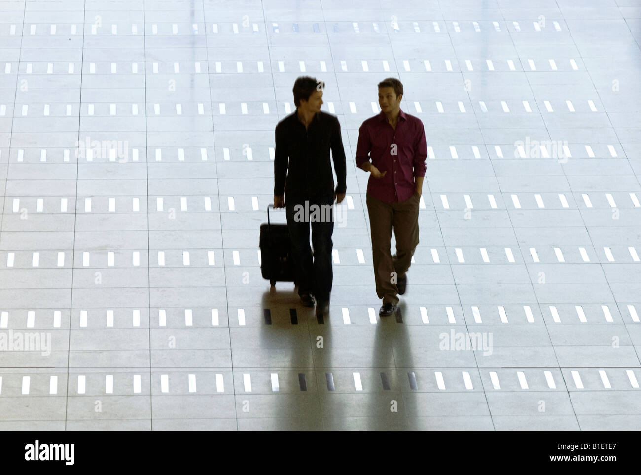 Mid adult man walking with a young man at an airport Stock Photo - Alamy