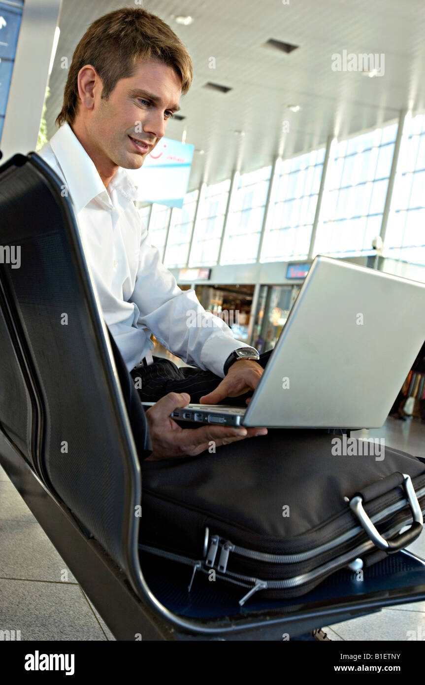 Businessman using a laptop at an airport lounge Stock Photo - Alamy