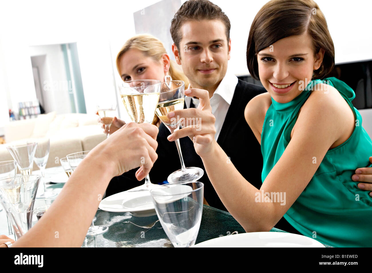 Portrait of a young woman toasting with champagne at a dinner party ...