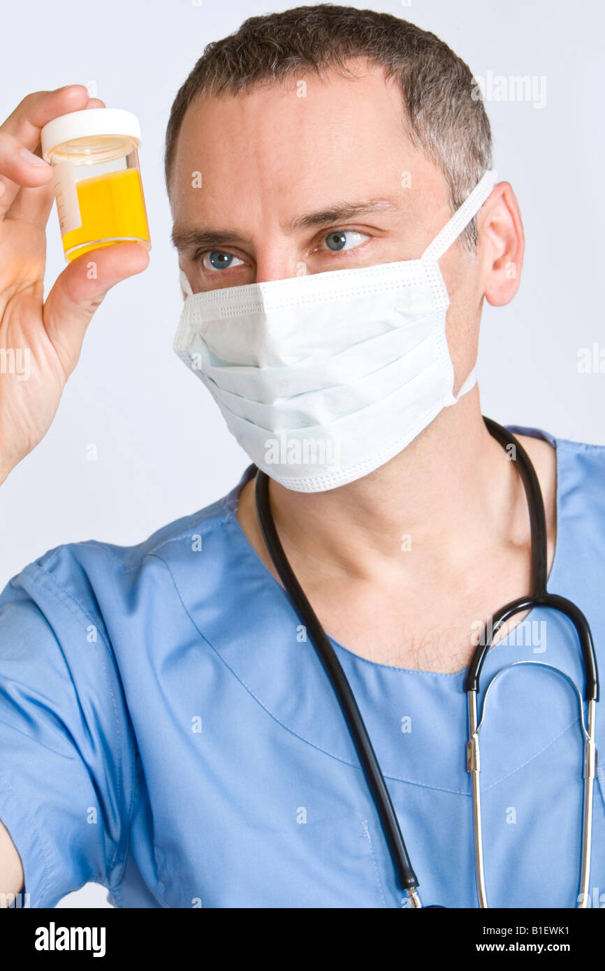 A male doctor in scrubs with a stethoscope examines a sample pot ...