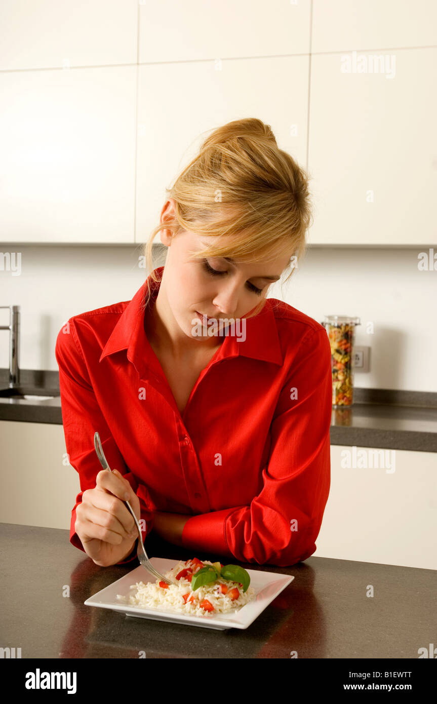 Young woman leaning against a kitchen counter and holding a fork Stock ...