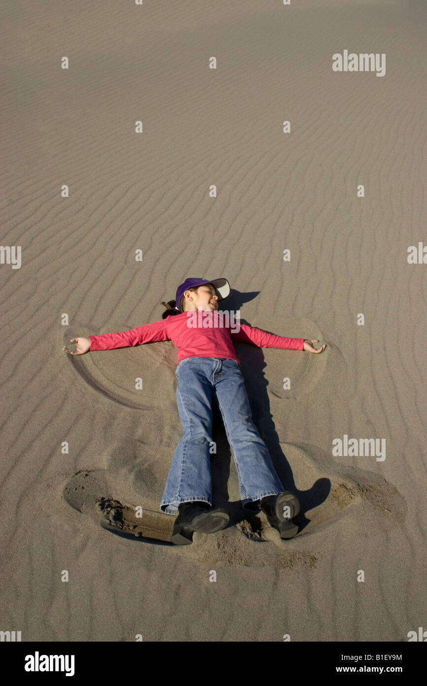 Young girl making a "snow angel" on a sand dune at Bruneau Dunes State ...