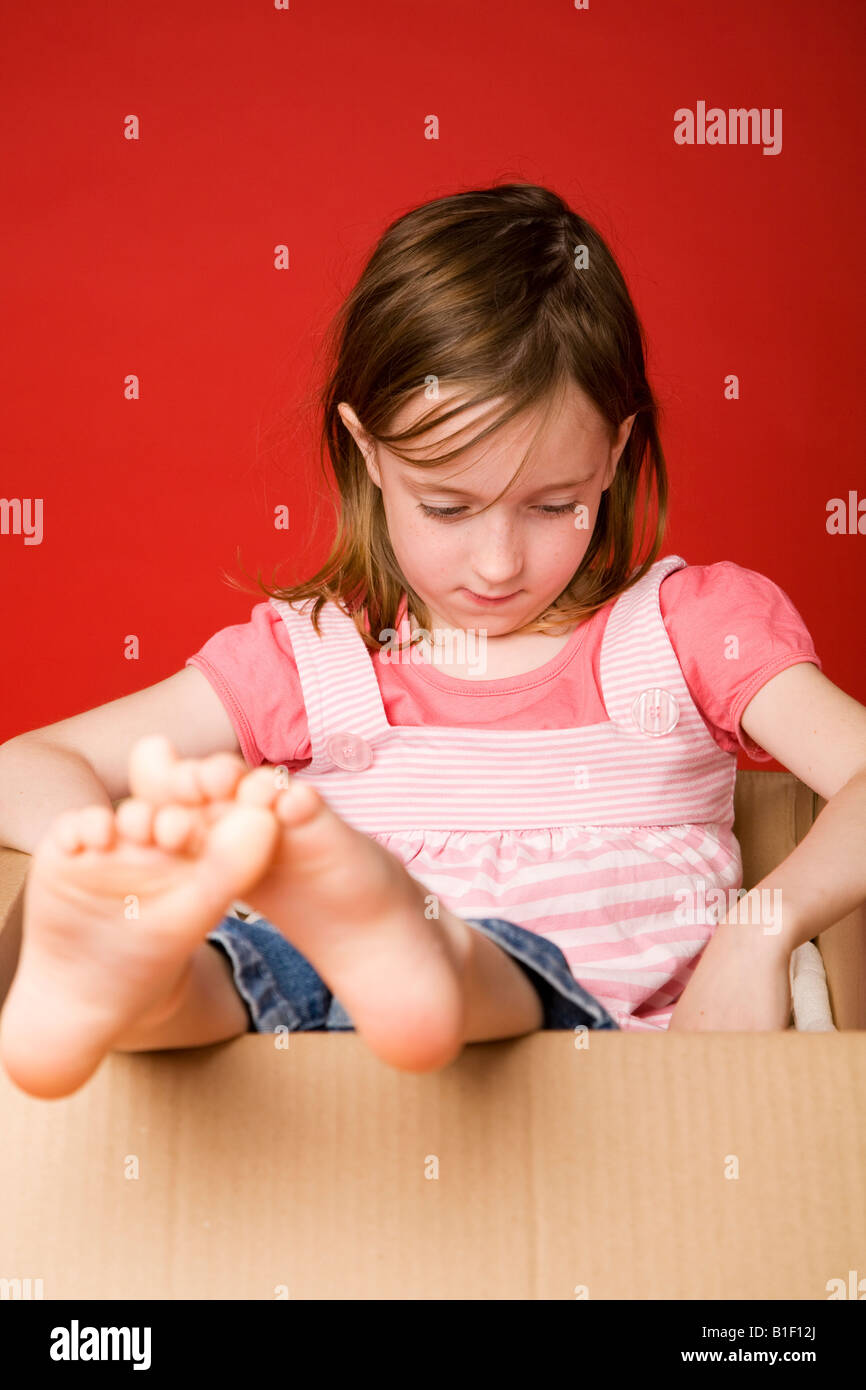 Litter girl sat in cardboard box on a red background Stock Photo - Alamy