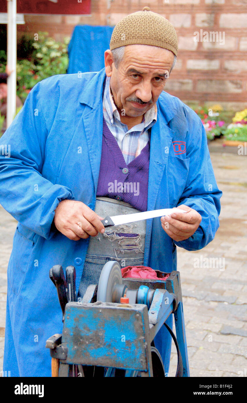 A knife-sharpener stands while he works, outside the spice bazaar in ...