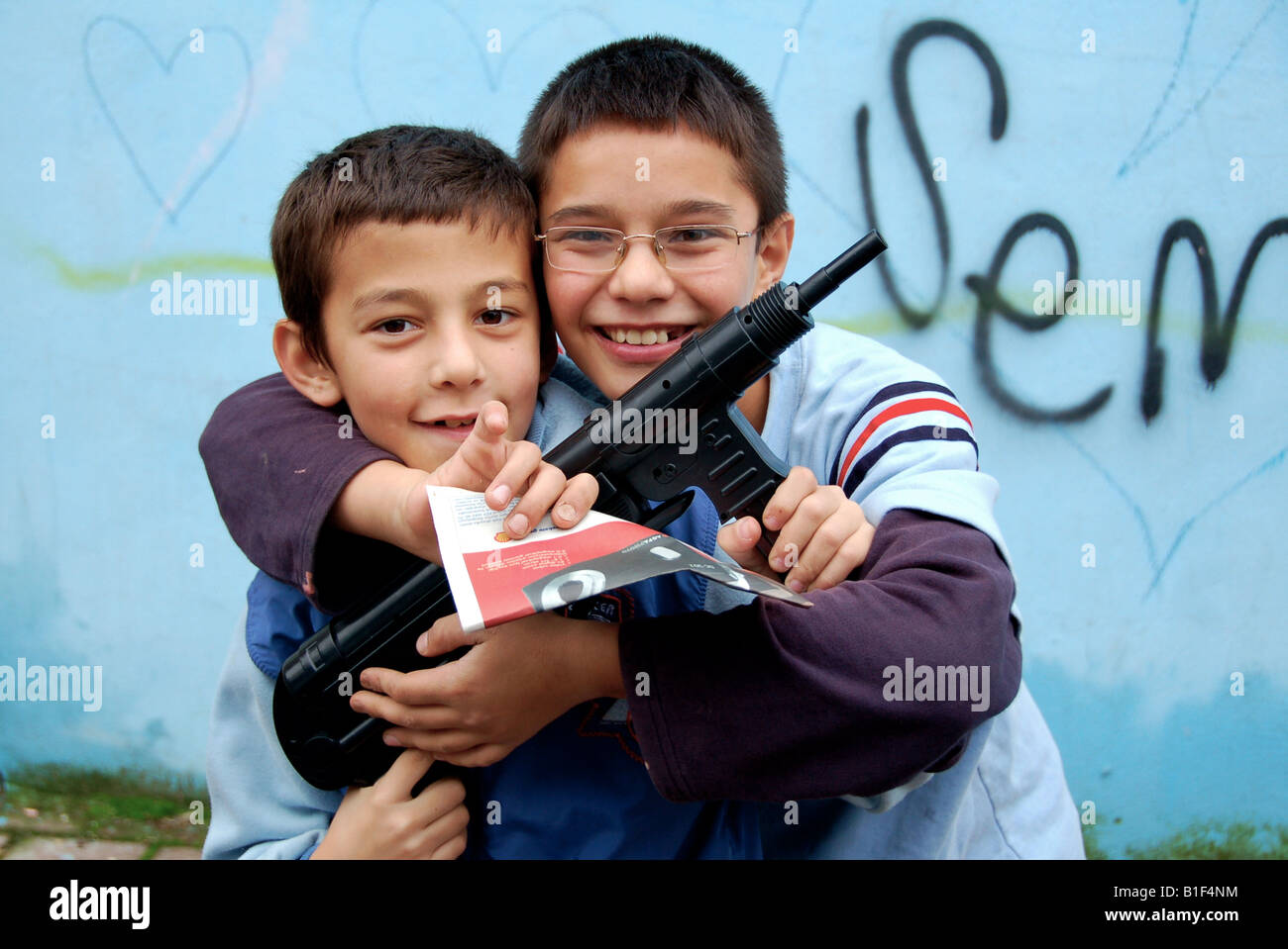 Two young friends play with a toy machine gun on the streets of Balat ...