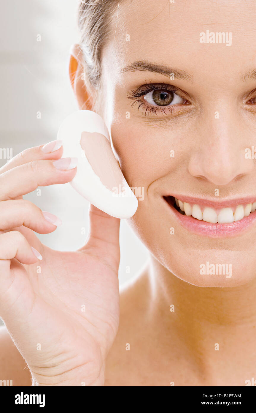 Portrait of a young woman applying face powder Stock Photo - Alamy