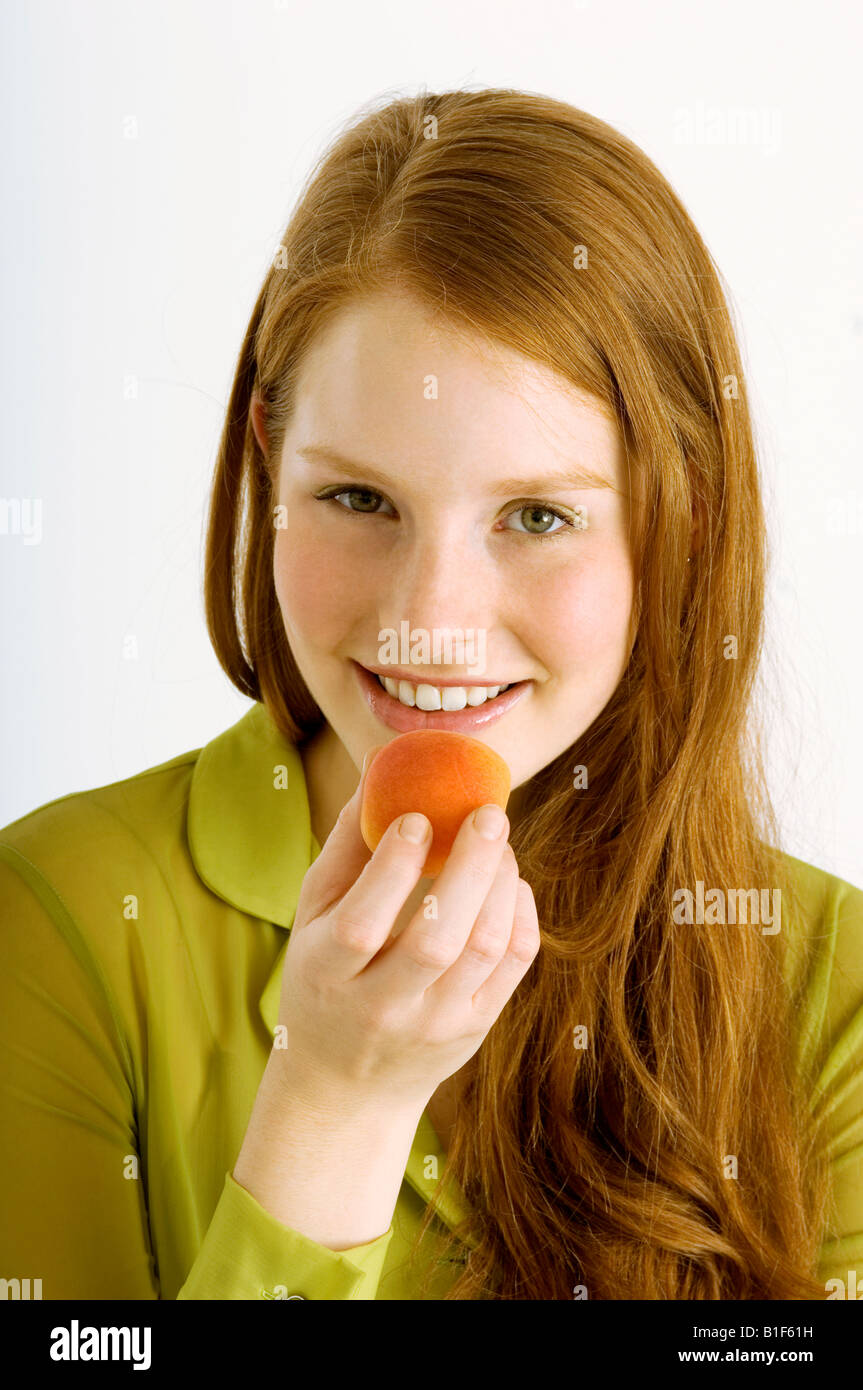 Portrait of a young woman eating an apricot and smiling Stock Photo - Alamy