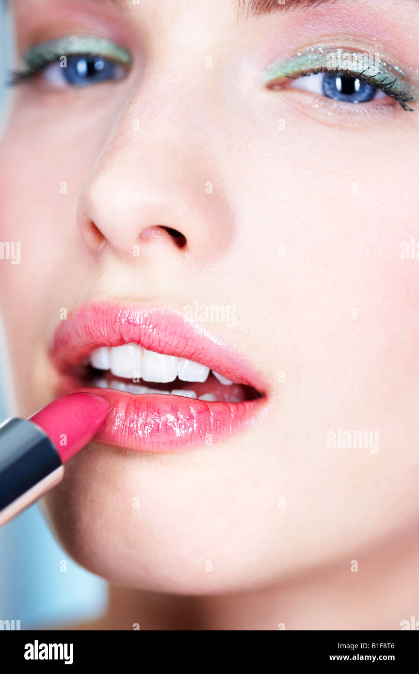 Portrait of young woman applying lipstick Stock Photo - Alamy