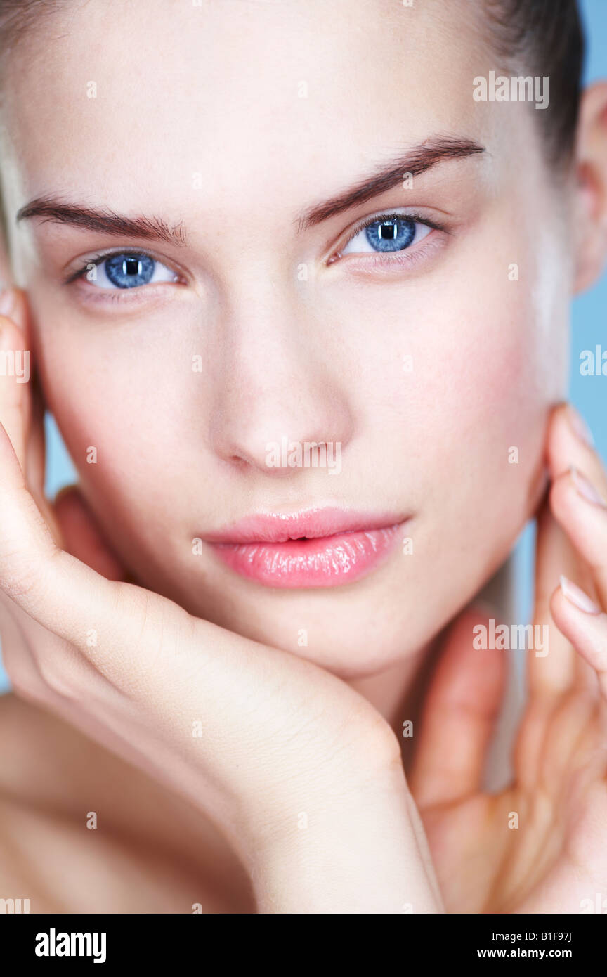 Portrait of young woman with hands on cheeks Stock Photo - Alamy