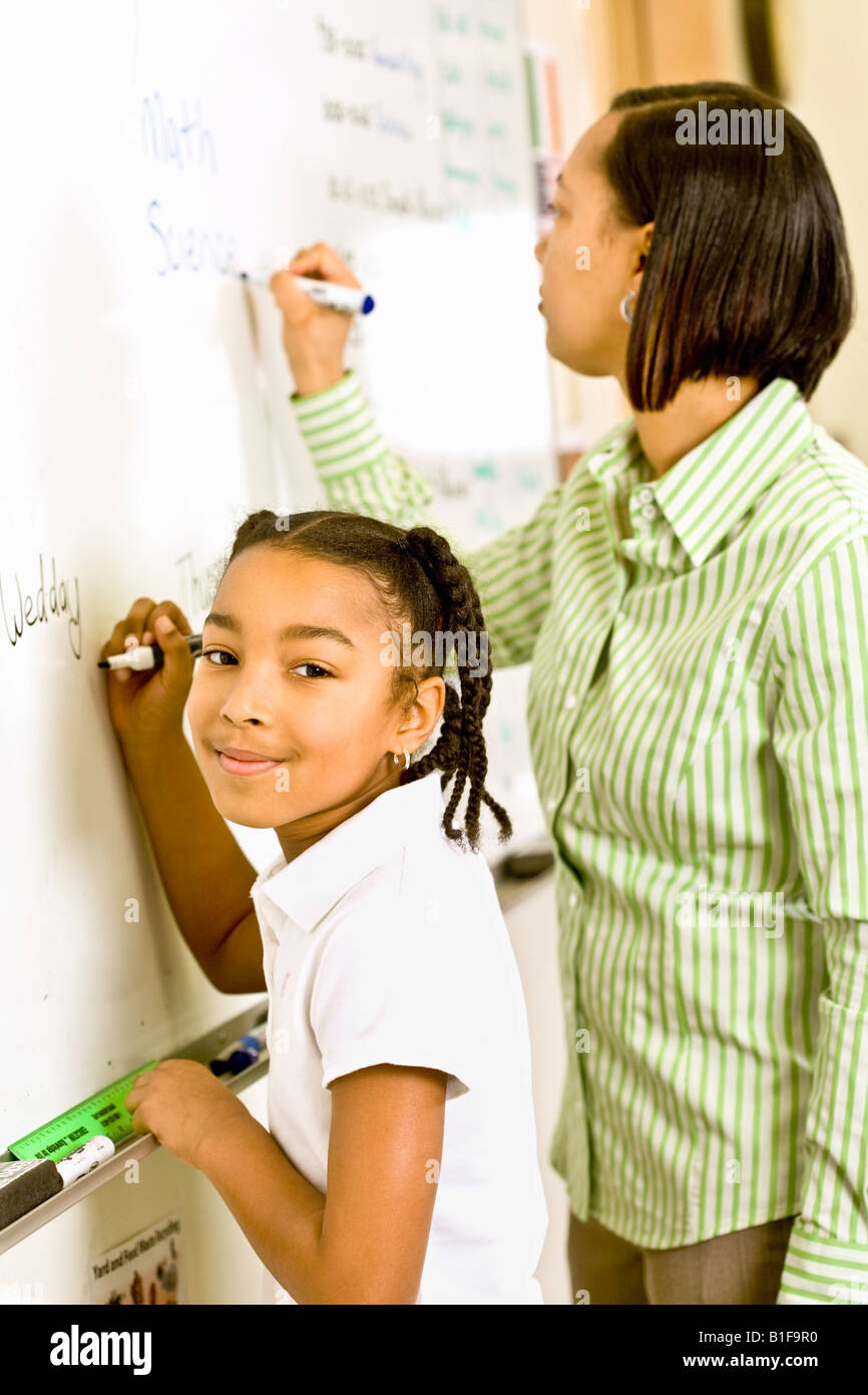 African teacher and student writing on whiteboard Stock Photo - Alamy