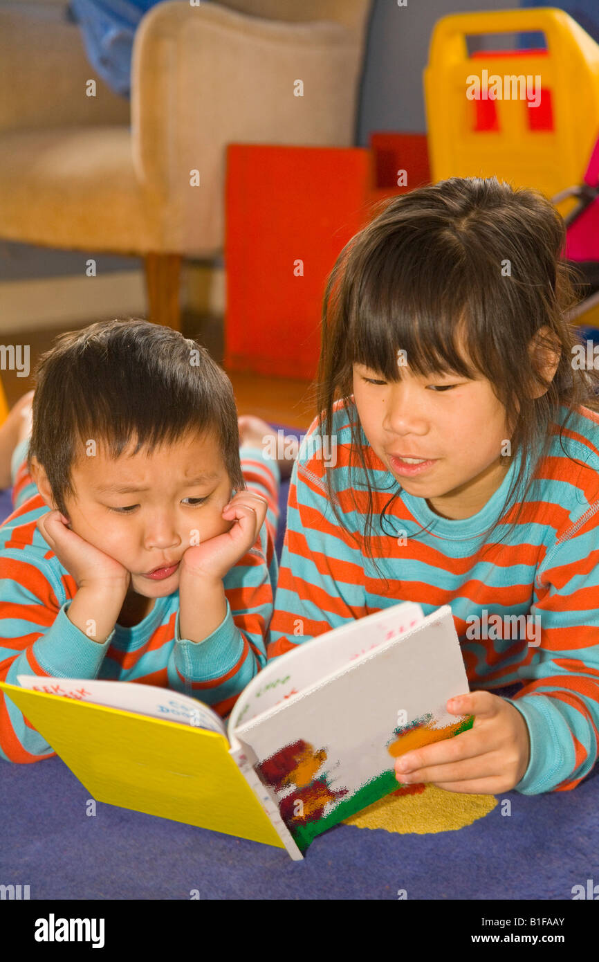 Asian siblings reading book Stock Photo - Alamy