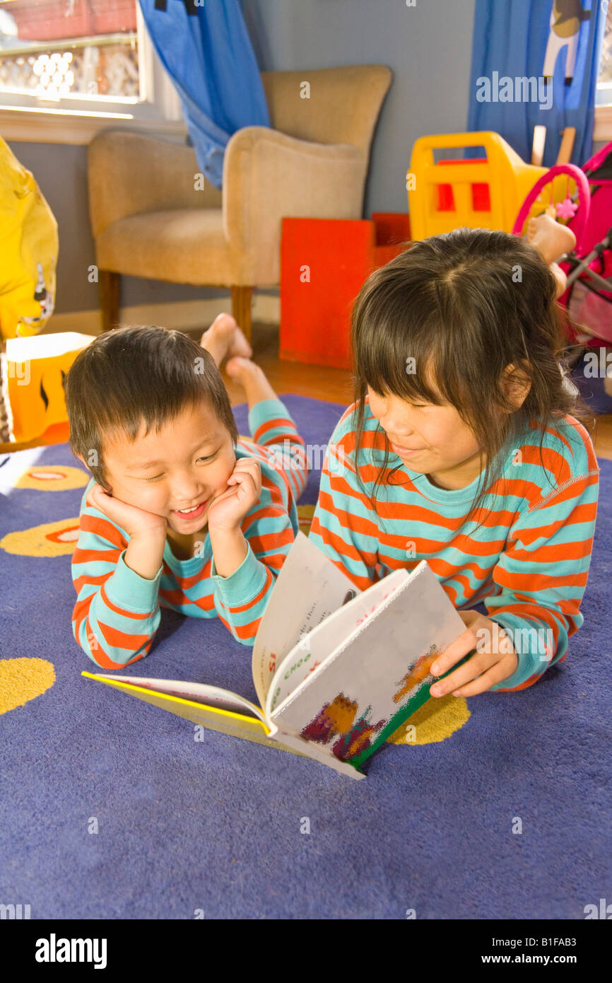 Asian siblings reading book Stock Photo - Alamy