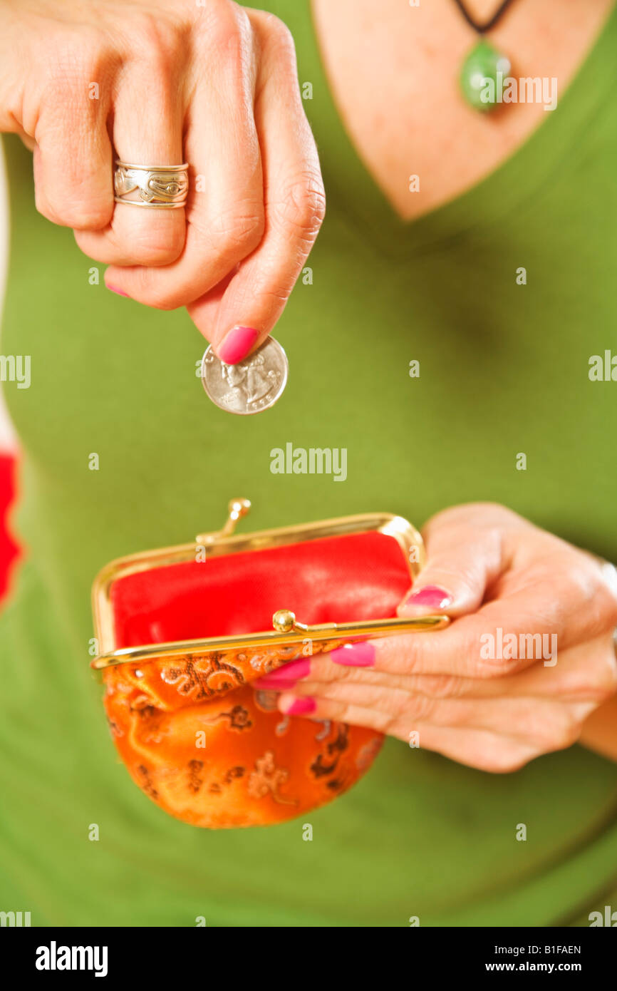 Woman dropping coin in purse Stock Photo - Alamy