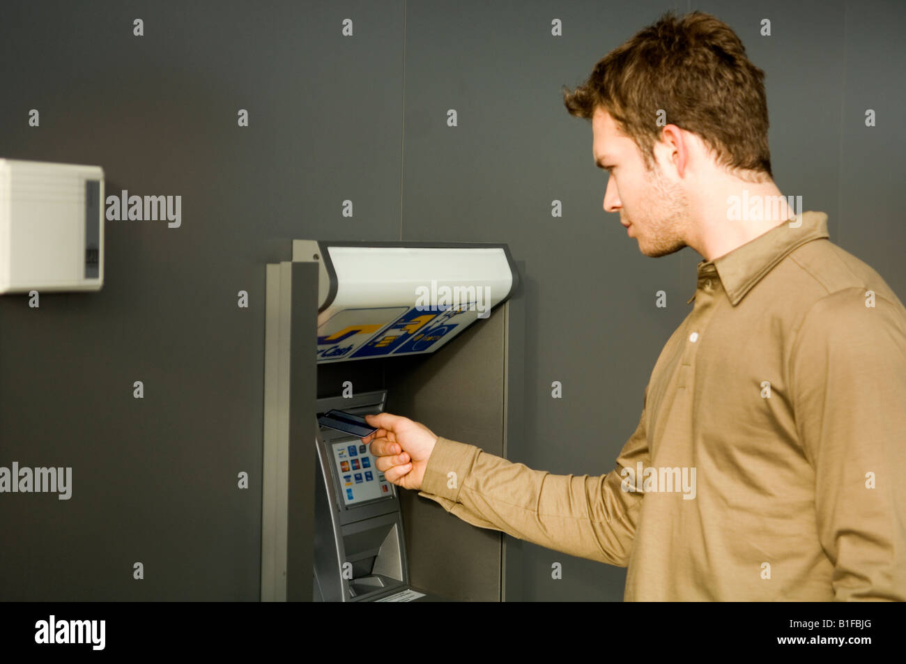 Young man using an ATM Stock Photo - Alamy