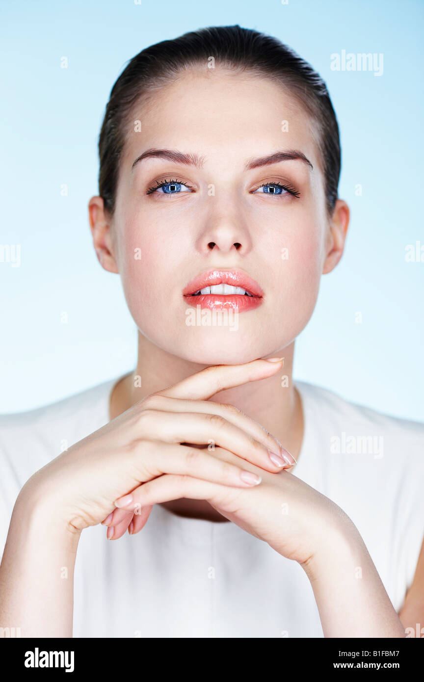 Portrait of young woman with hands on chin Stock Photo - Alamy