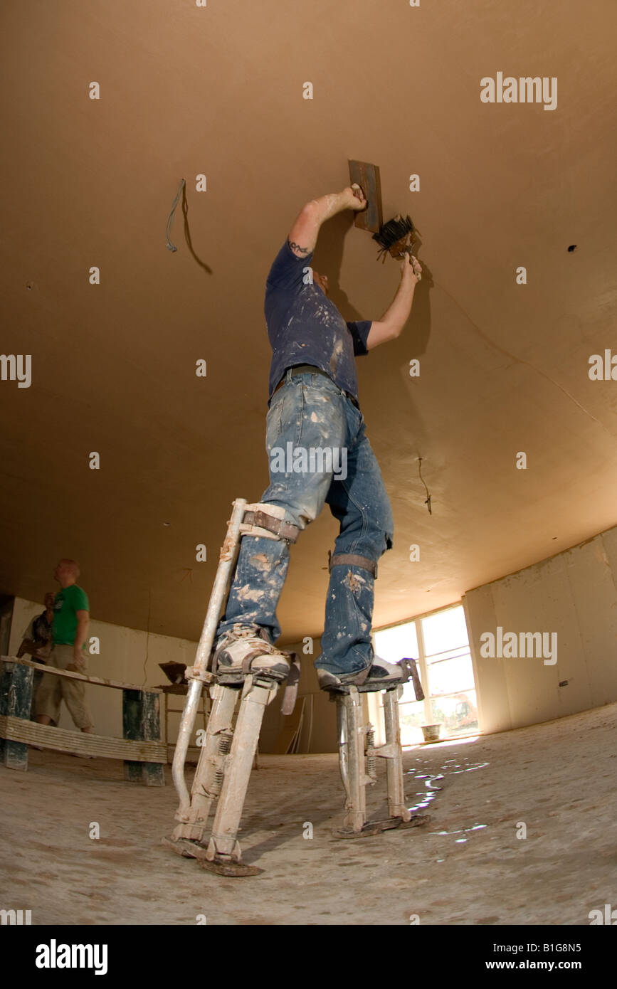 workman plasterer working on stilts Stock Photo - Alamy