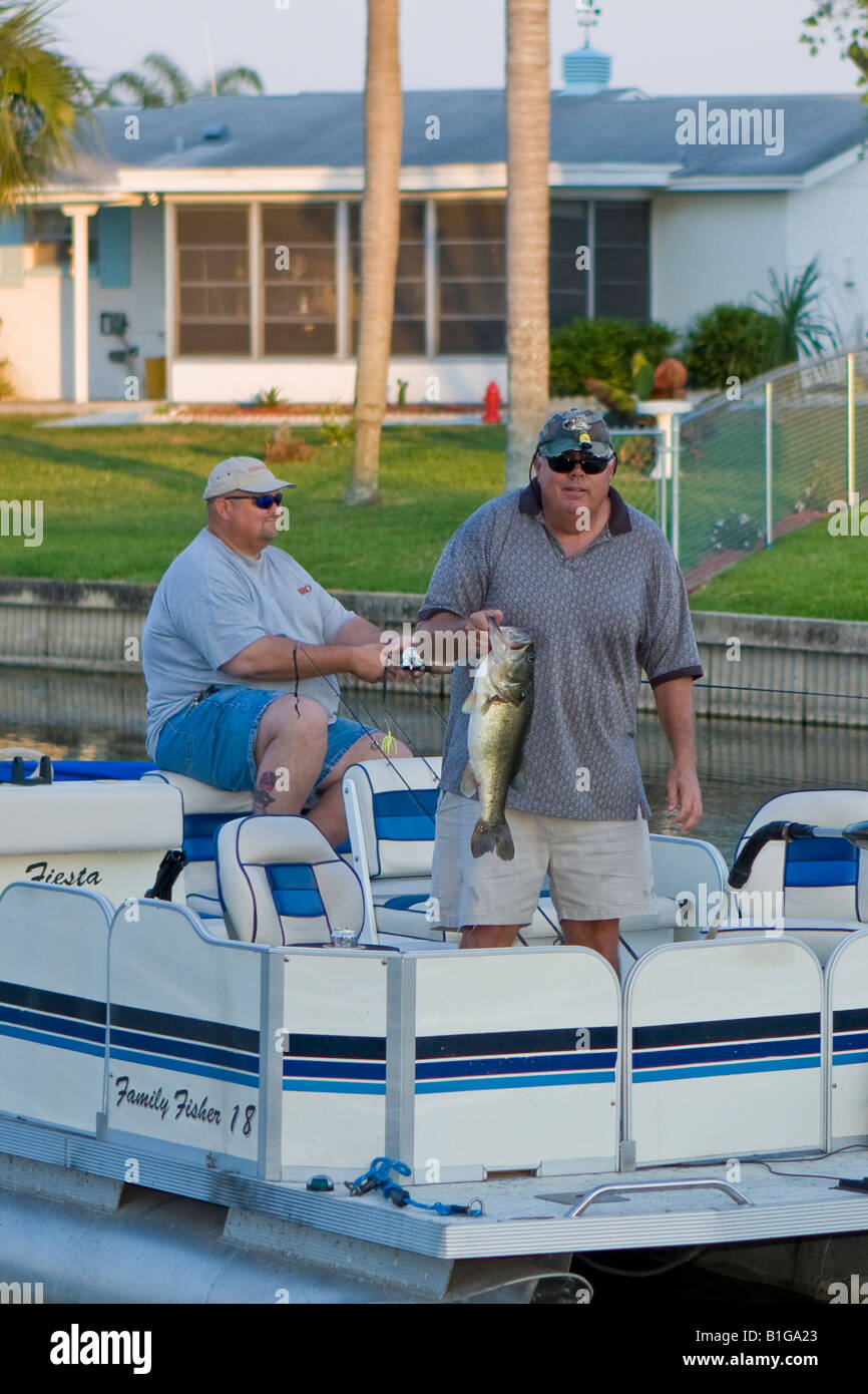 Two Fisherman on a Pontoon Boat Holding a Large Fish Stock Photo - Alamy