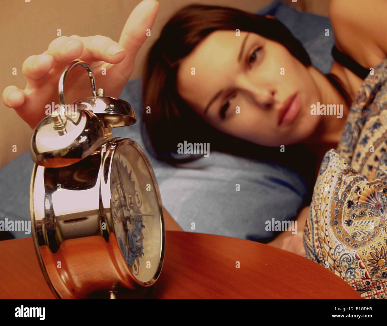 A young woman wakes up with alarm bell Stock Photo - Alamy