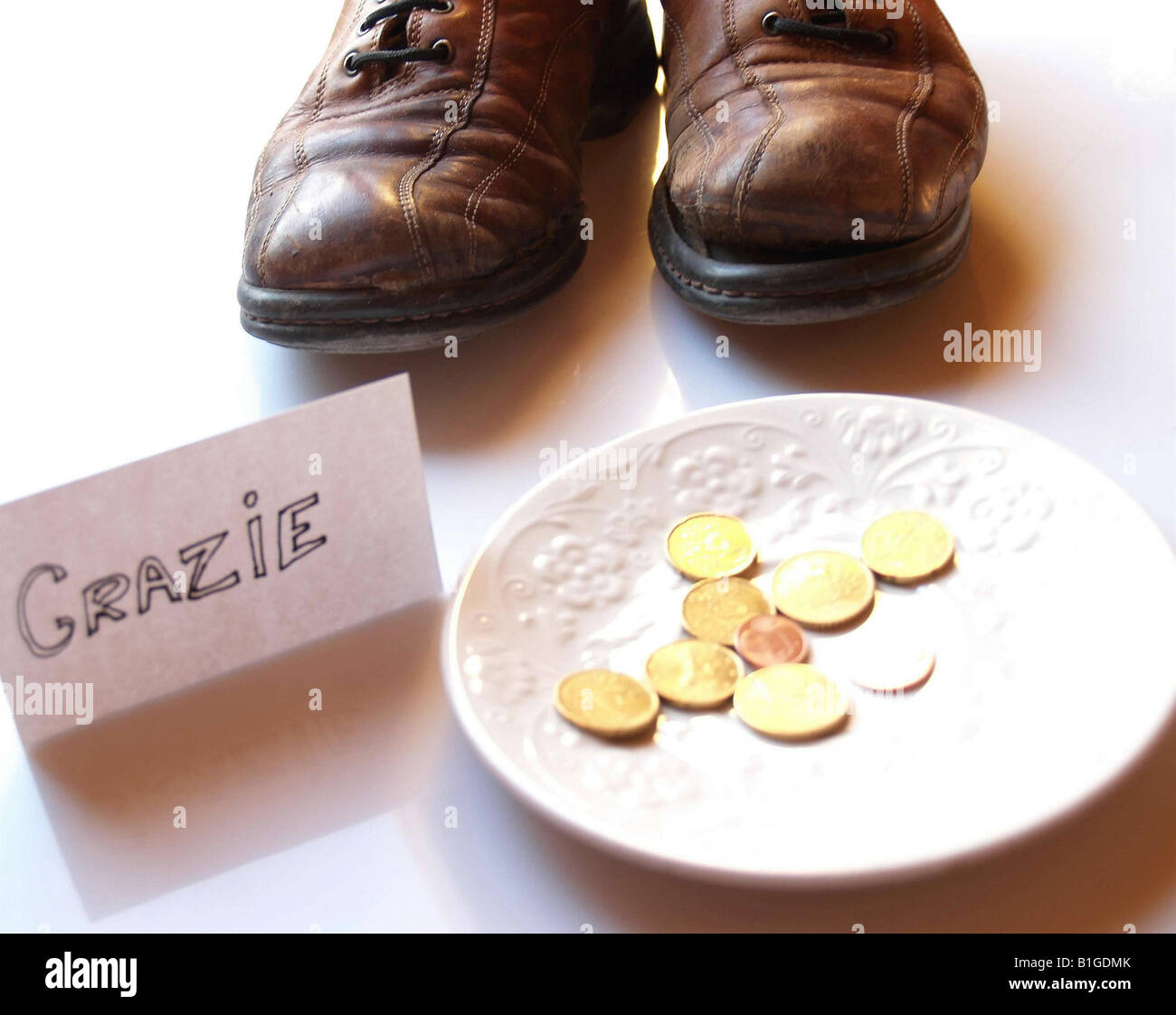 Closeup of begging plate with coins and shoes Stock Photo - Alamy