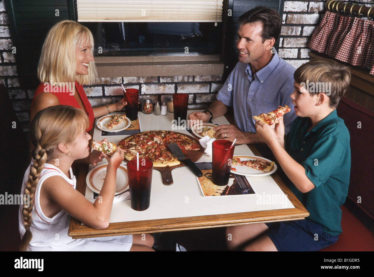 Young family dining together,eating pizza, laughing playing, Miami ...