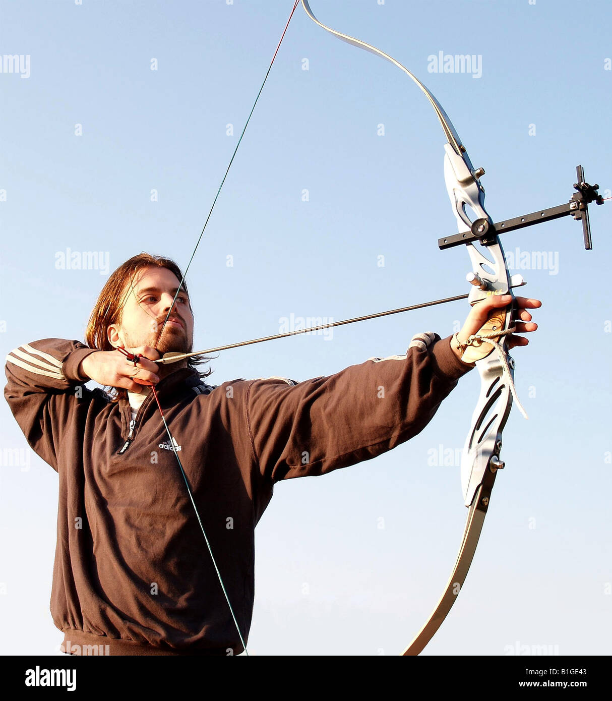 Front view of a young man aiming with bow and arrow Stock Photo - Alamy