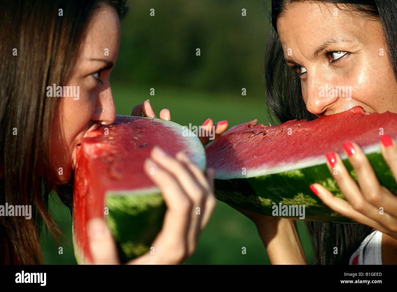 Profile of two young woman eating watermelon Stock Photo - Alamy