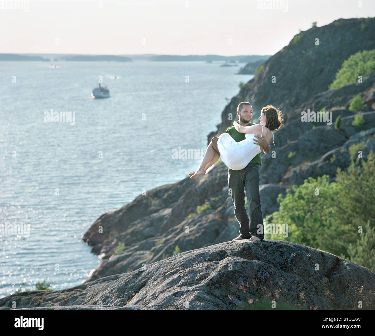 Young man carrying a young woman on a rock Stock Photo - Alamy