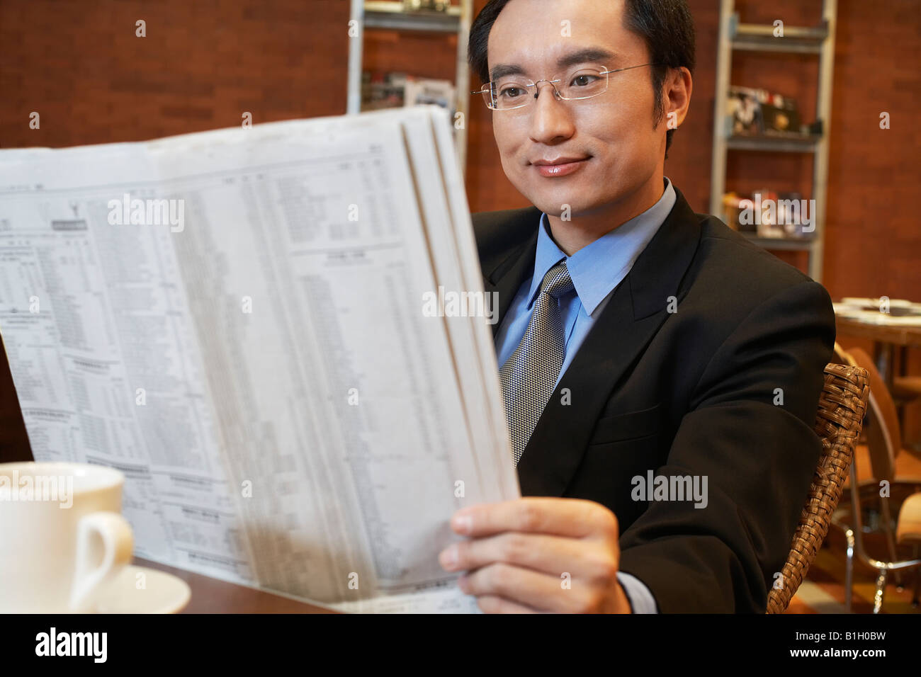 China, Businessman reading newspaper at cafe table, close-up Stock ...