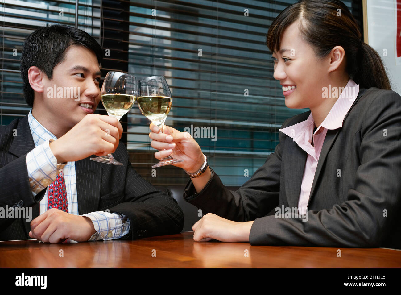 Two business people toasting with wine glasses, sitting in cafe Stock ...