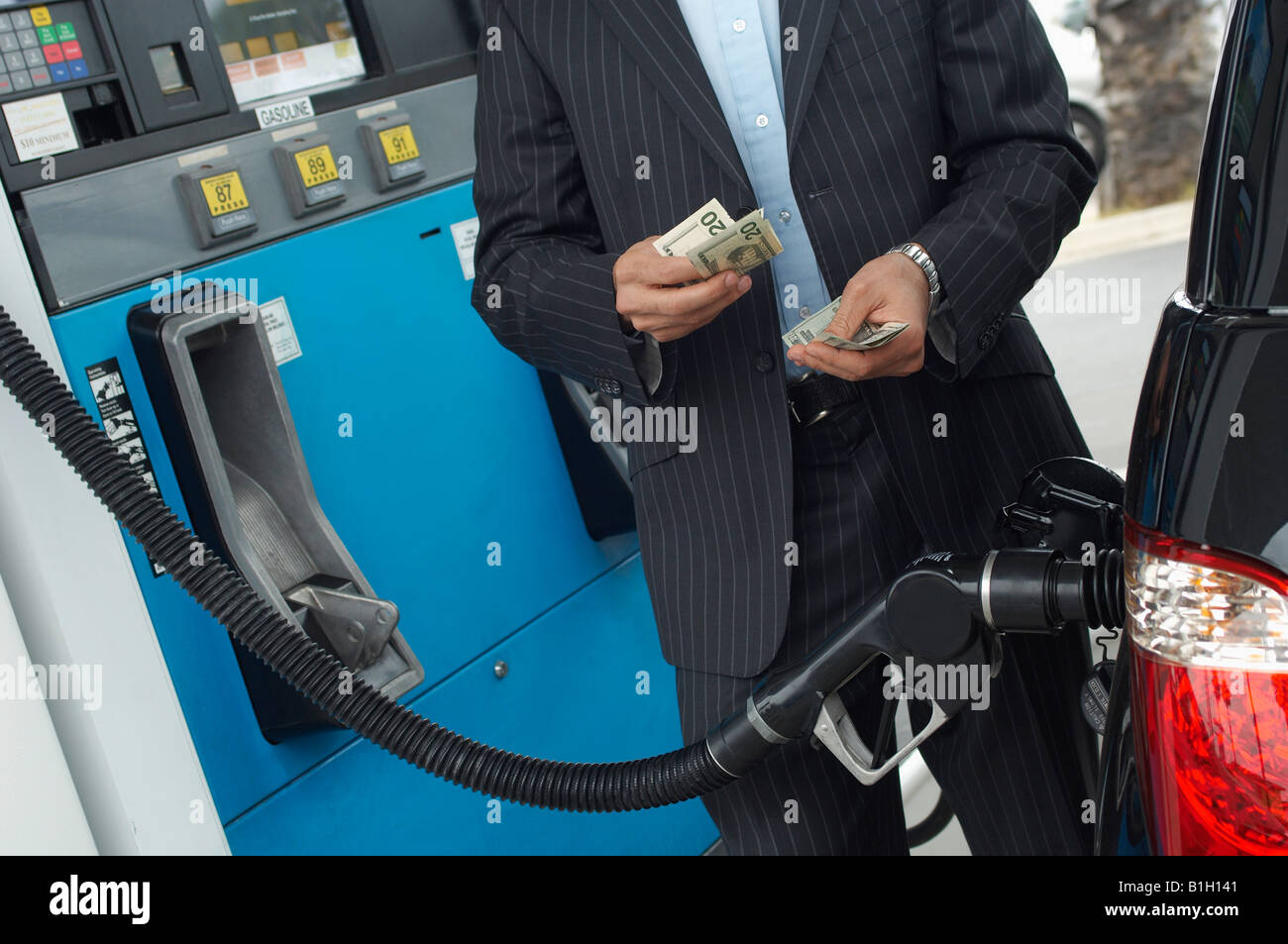 Man counting money over gas pump in car, mid section Stock Photo - Alamy