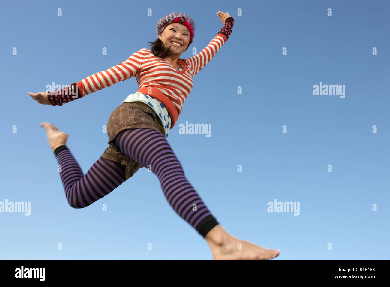 Young woman jumping in striped outfit Stock Photo - Alamy