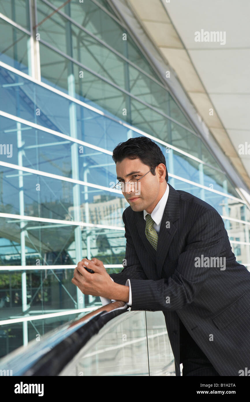 Businessman leaning on railing outside office building Stock Photo - Alamy