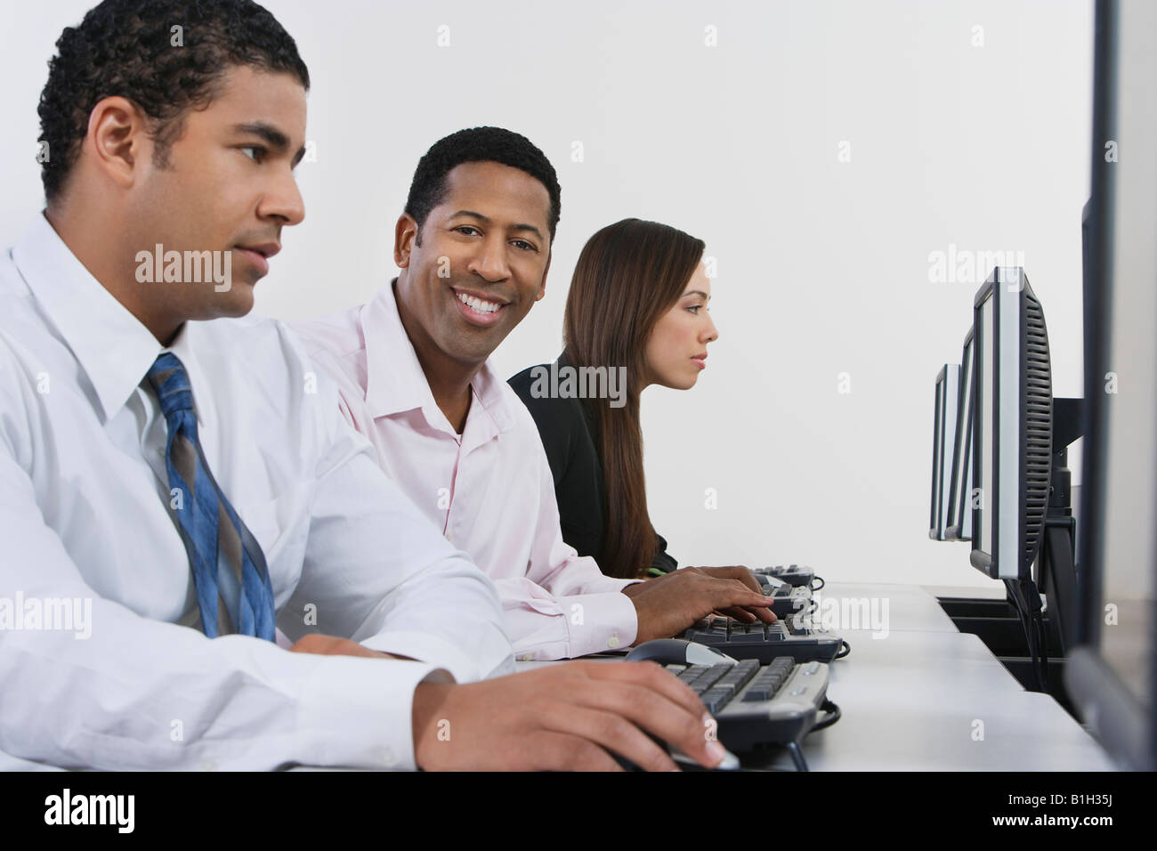 Three business people using computers in office Stock Photo - Alamy