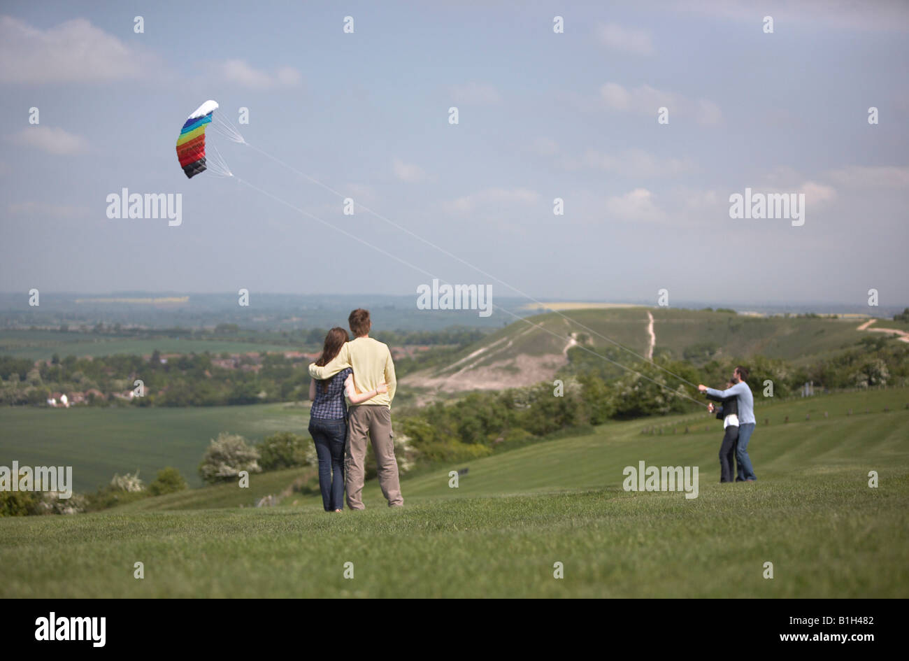 Couple watching friends flying kite, Dunstable Downs Stock Photo - Alamy