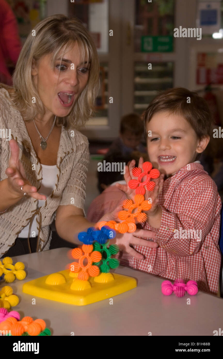 teacher or teaching assistant helping a child play with a building toy ...