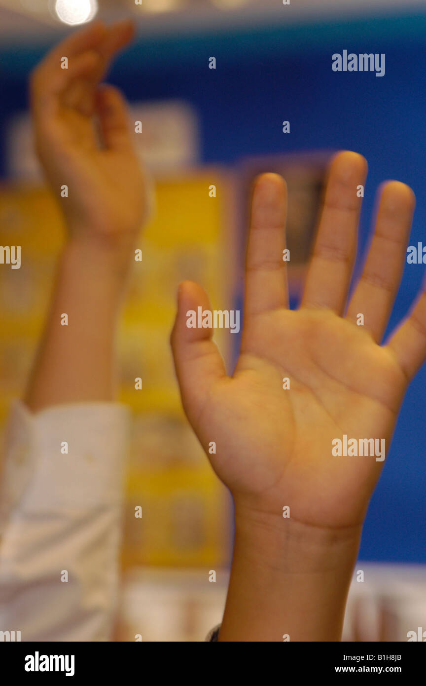 schoolchildren raising their hands in class Stock Photo - Alamy
