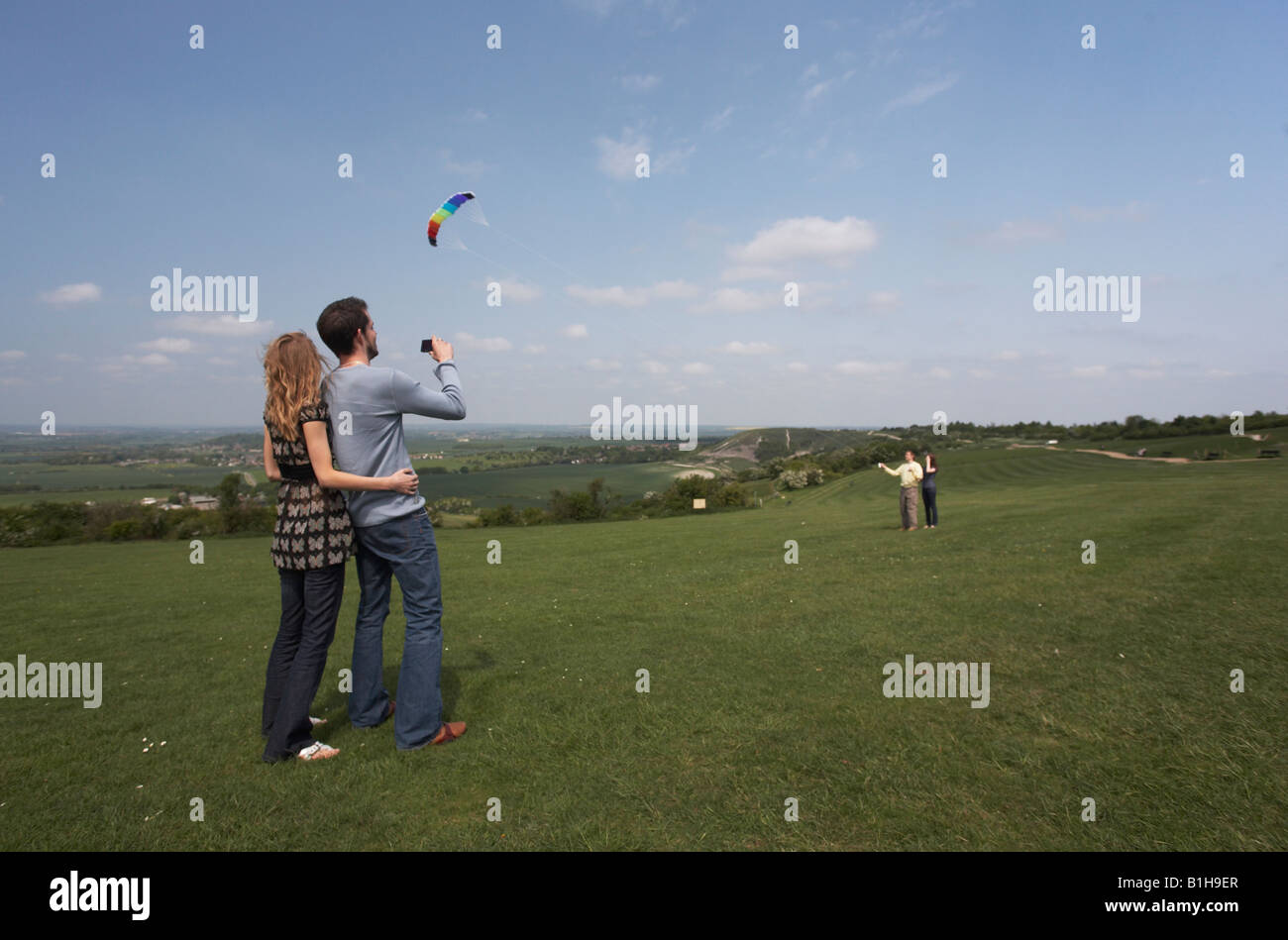 Young couple photographing friends flying kite Stock Photo - Alamy