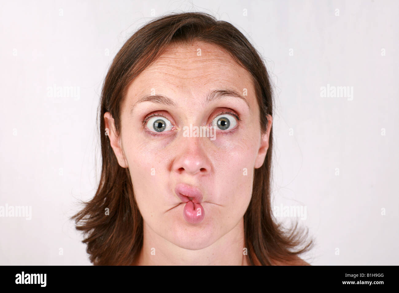 Young brunette woman pulling funny humorous comical duck face squashed ...