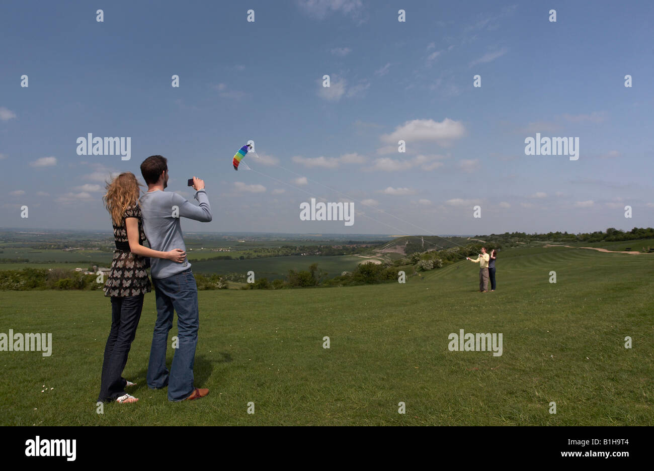Young couple photographing friends flying kite Stock Photo - Alamy