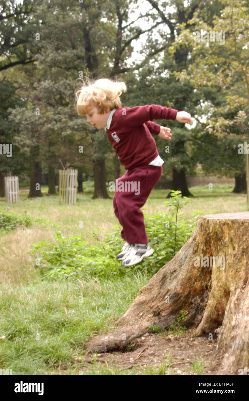 primary school child jumping off a log in the park Stock Photo - Alamy