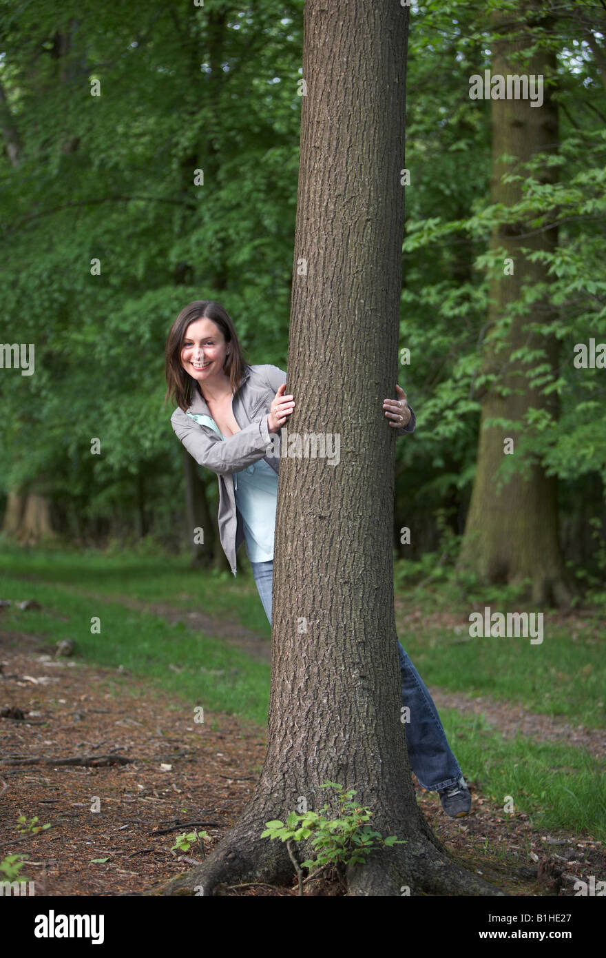 Woman hiding behind tree hi-res stock photography and images - Alamy