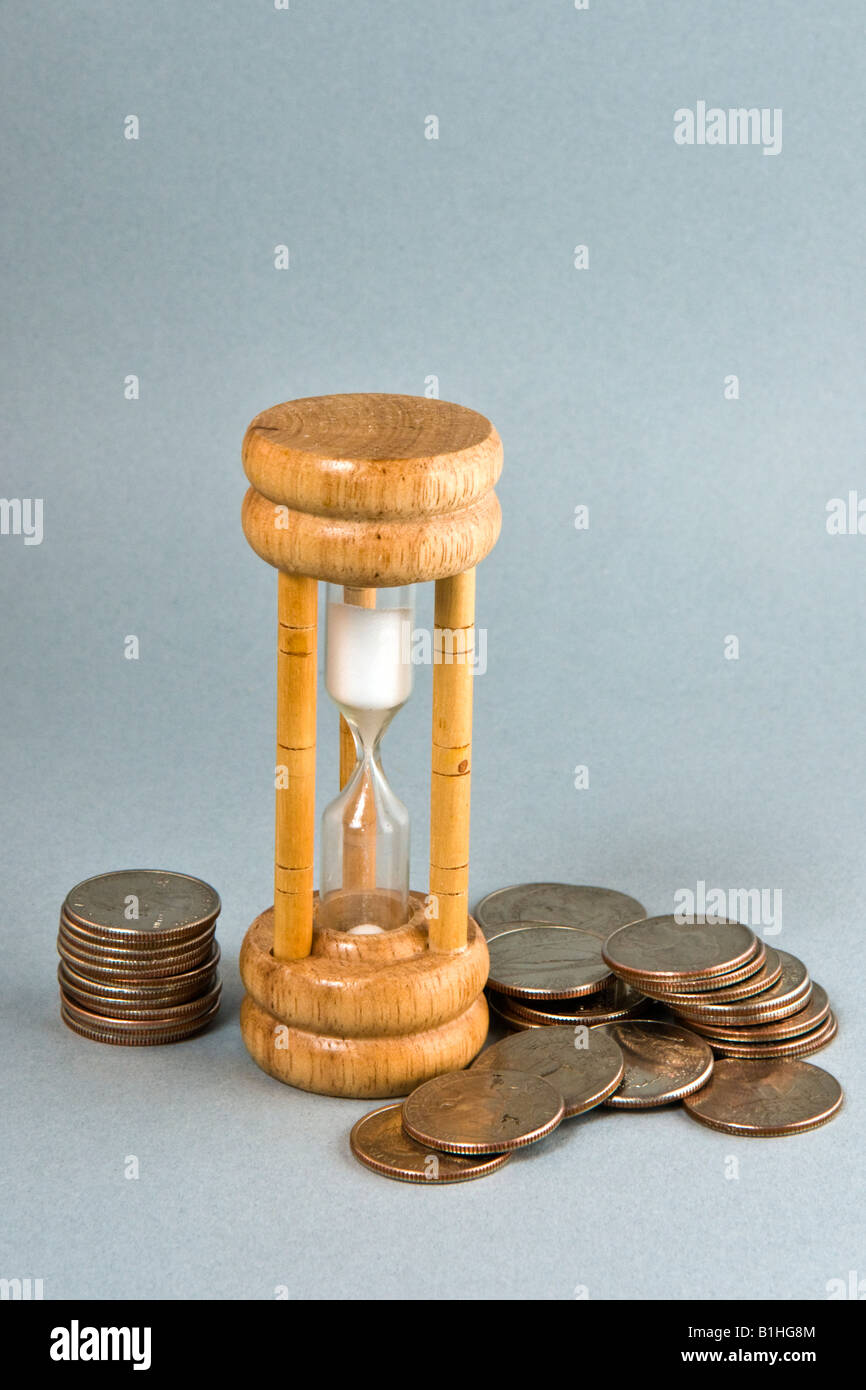 Egg timer and coins denoting time is money Stock Photo - Alamy