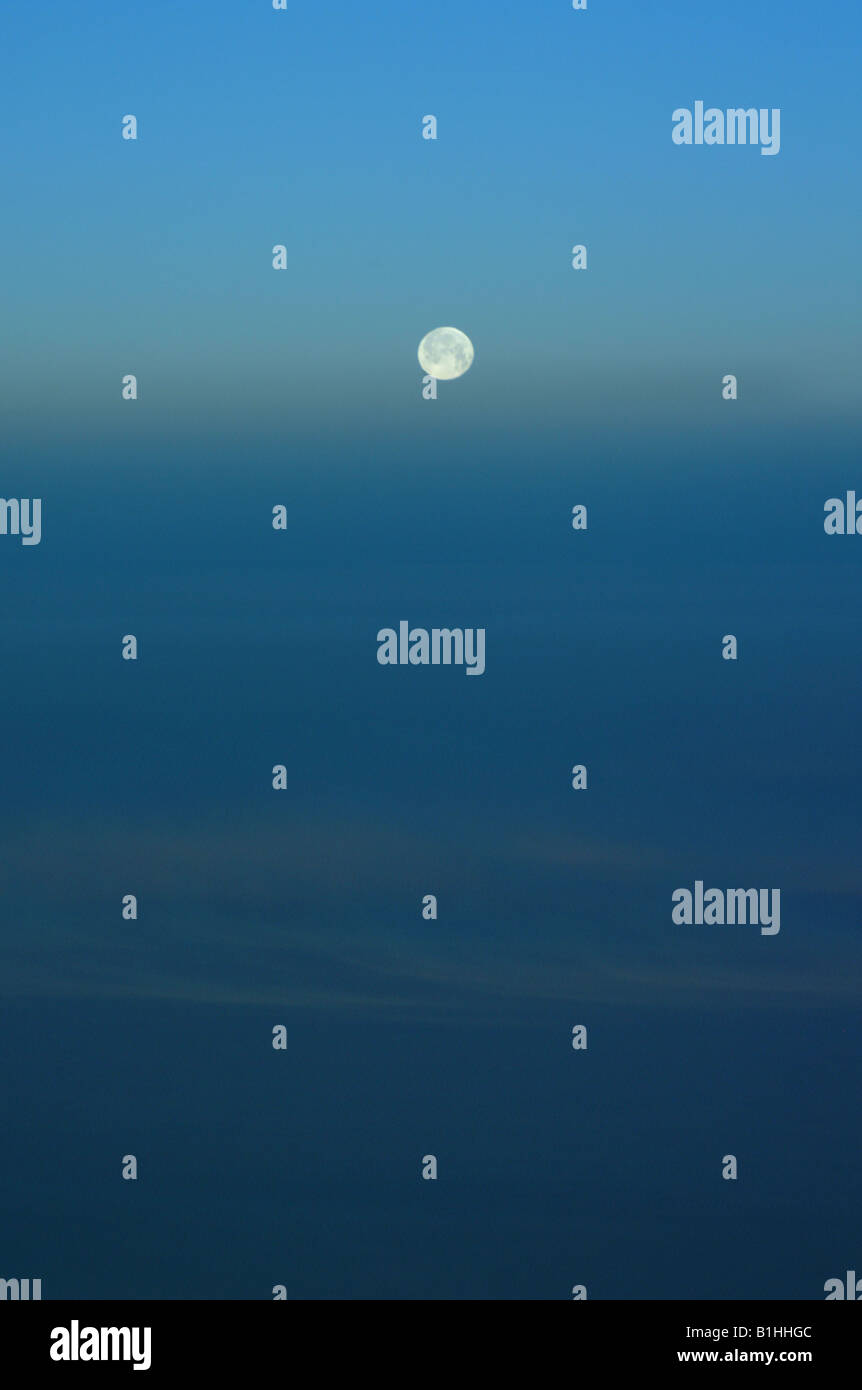 The moon as seen from altitude over hazy and darkening cloud against a ...