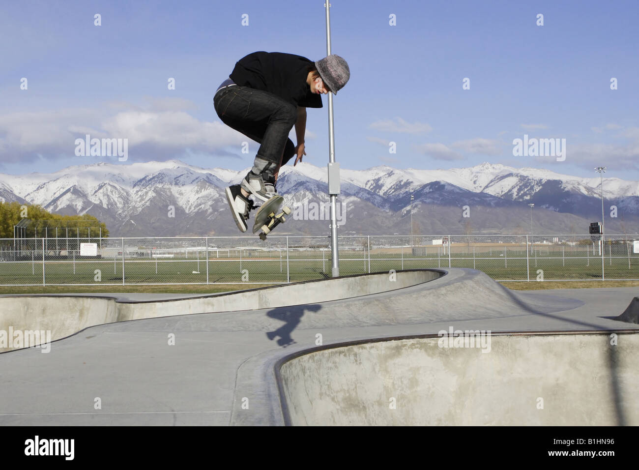 Teenage skateboarder flying high over concrete skate park Stock Photo ...